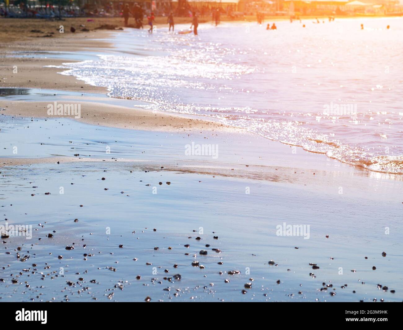 sea waves on sand beach with swimming peoples in background, toned ...