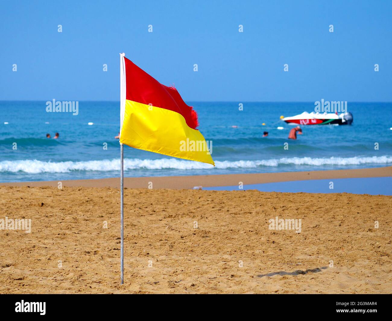 red and yellow flag on beach marking safe swimming area Stock Photo - Alamy