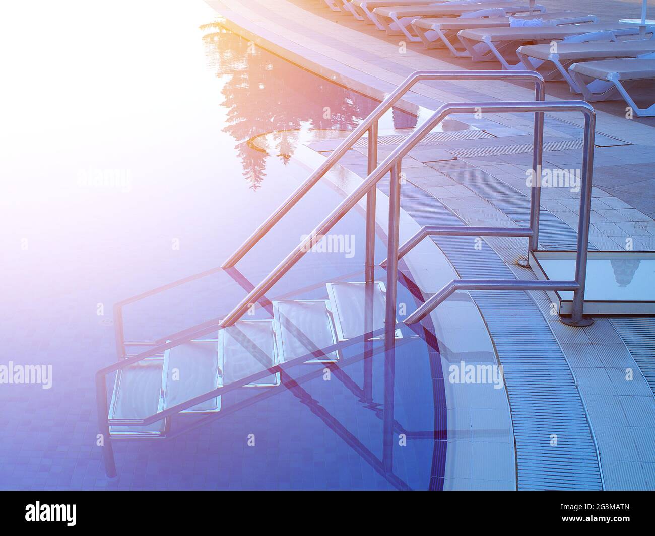 outdoor swimming pool in-pool ladder with sunbeds in background, early ...