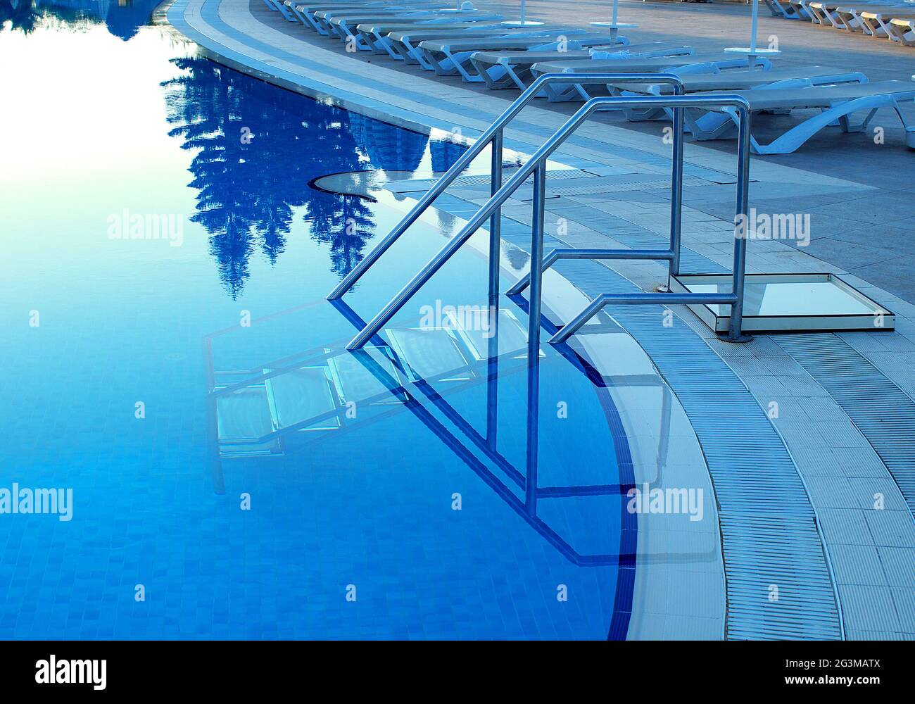 outdoor swimming pool in-pool ladder with sunbeds in background, early ...