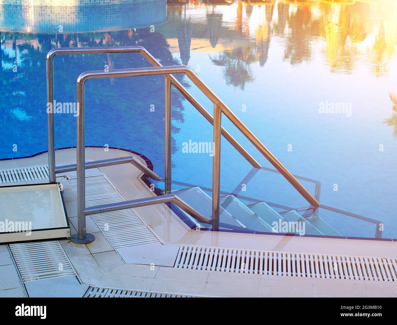 outdoor swimming pool in-pool ladder with trees and umbrellas ...