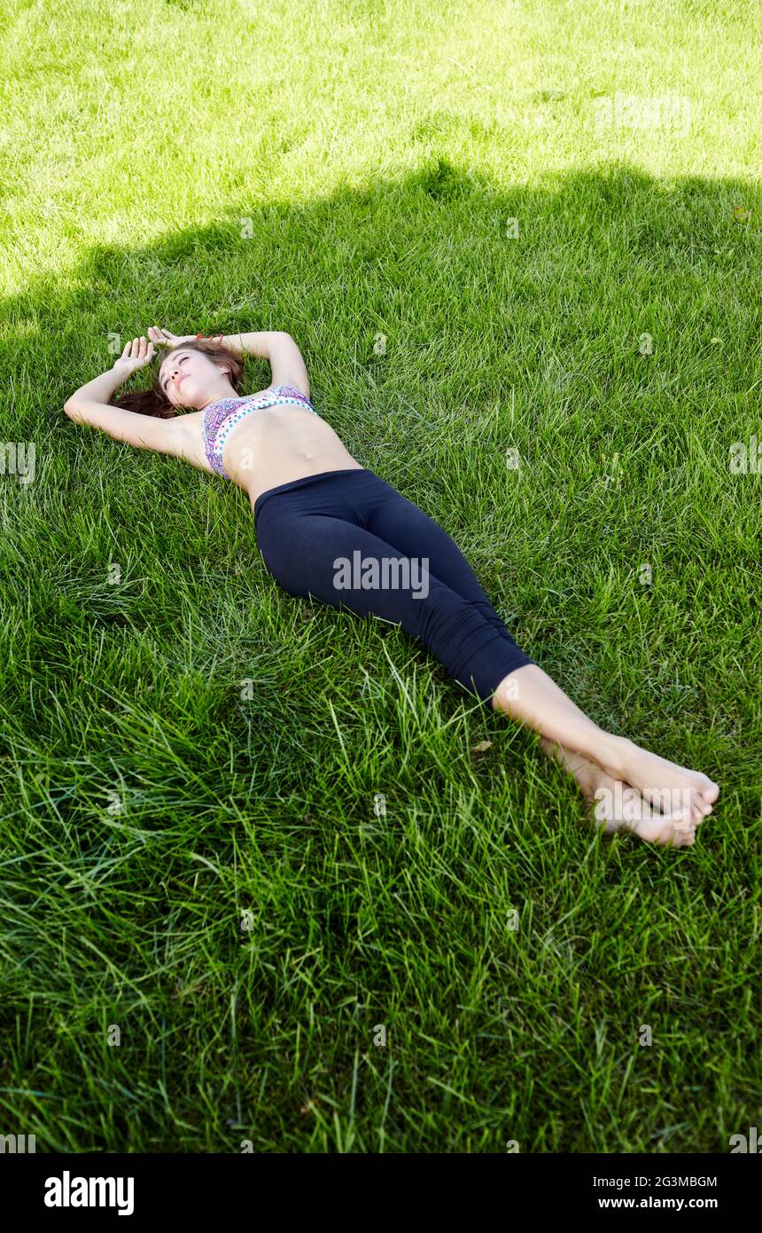 Portrait of a smiling girl lying on green grass. Woman relaxing ...
