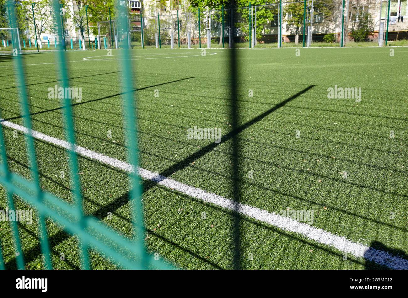 Lawn field for playing football behind the green fence mesh. Close-up ...