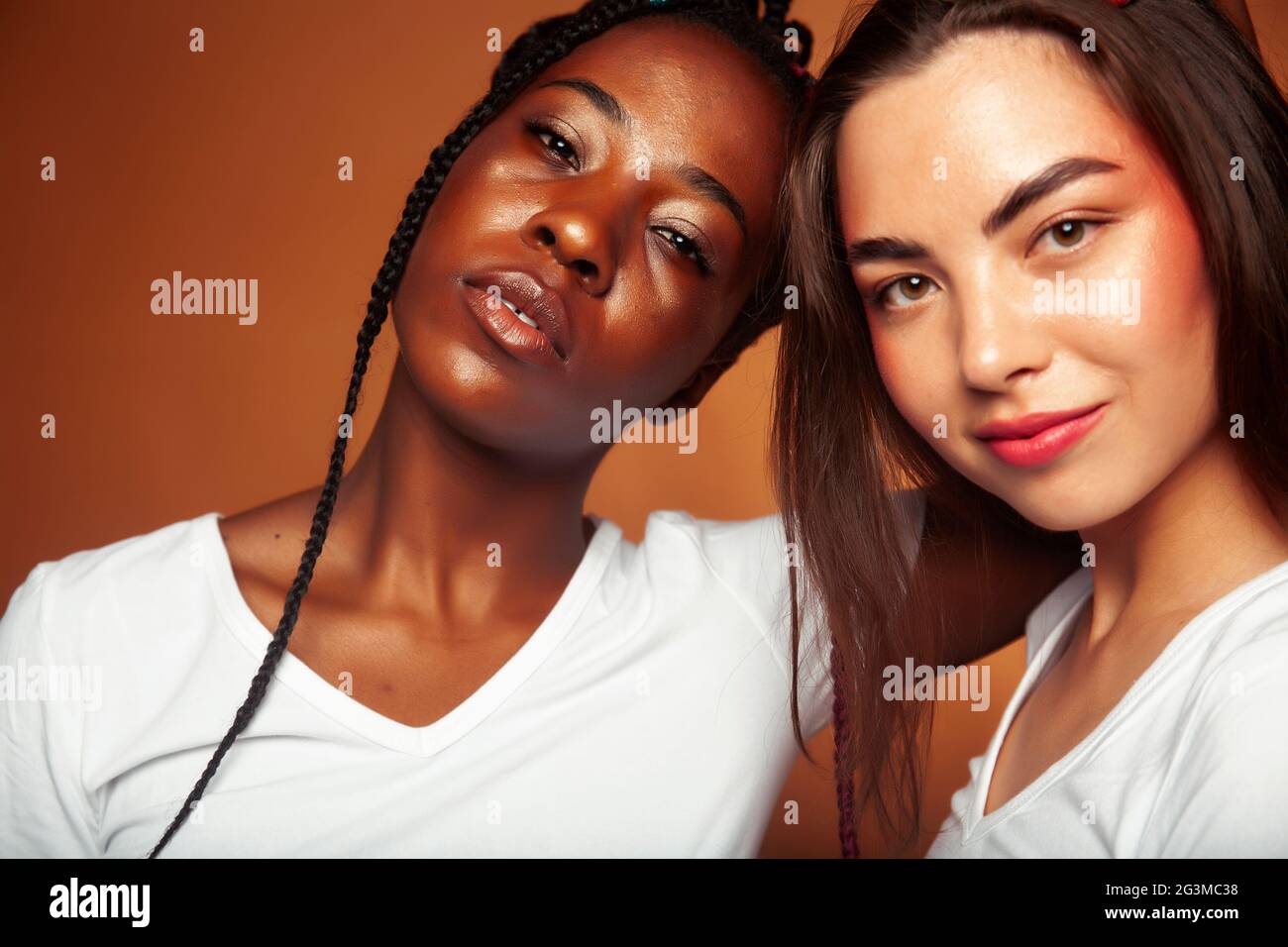 young pretty asian, afro woman posing cheerful together on brown ...