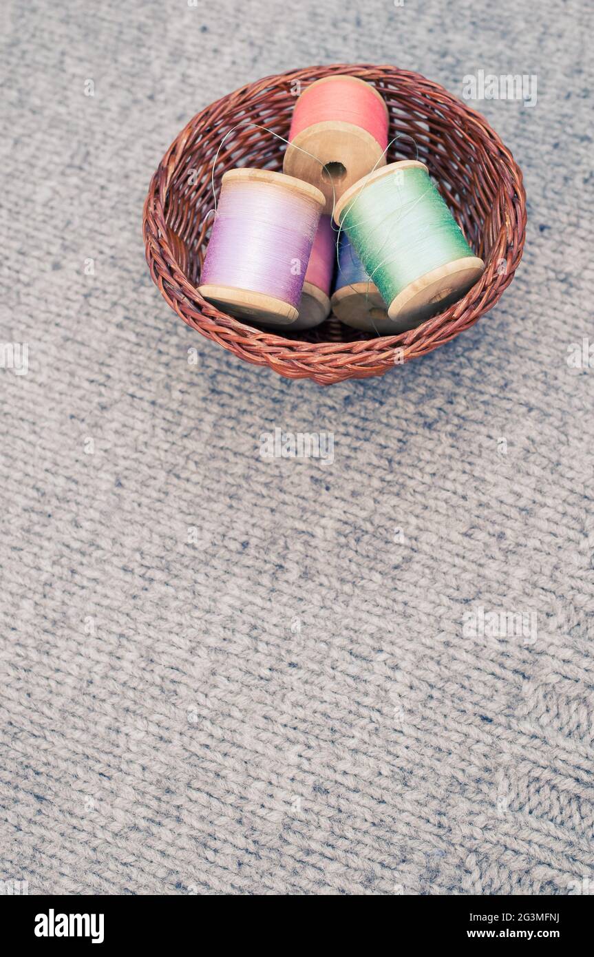 Basket of colorful sewing threads on a grey fabric with free space for ...