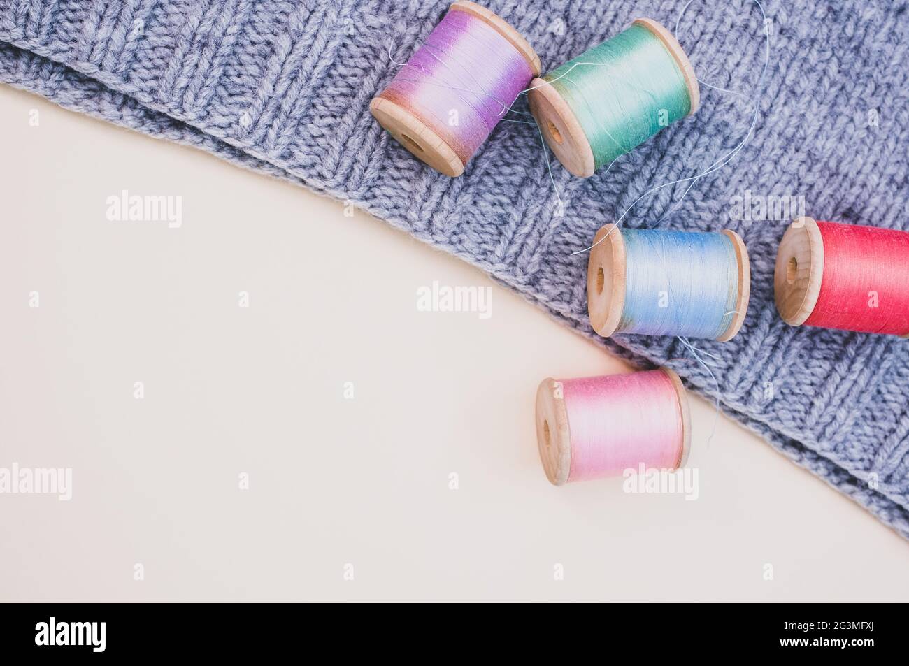 Colorful sewing threads with grey fabric on a light background with ...