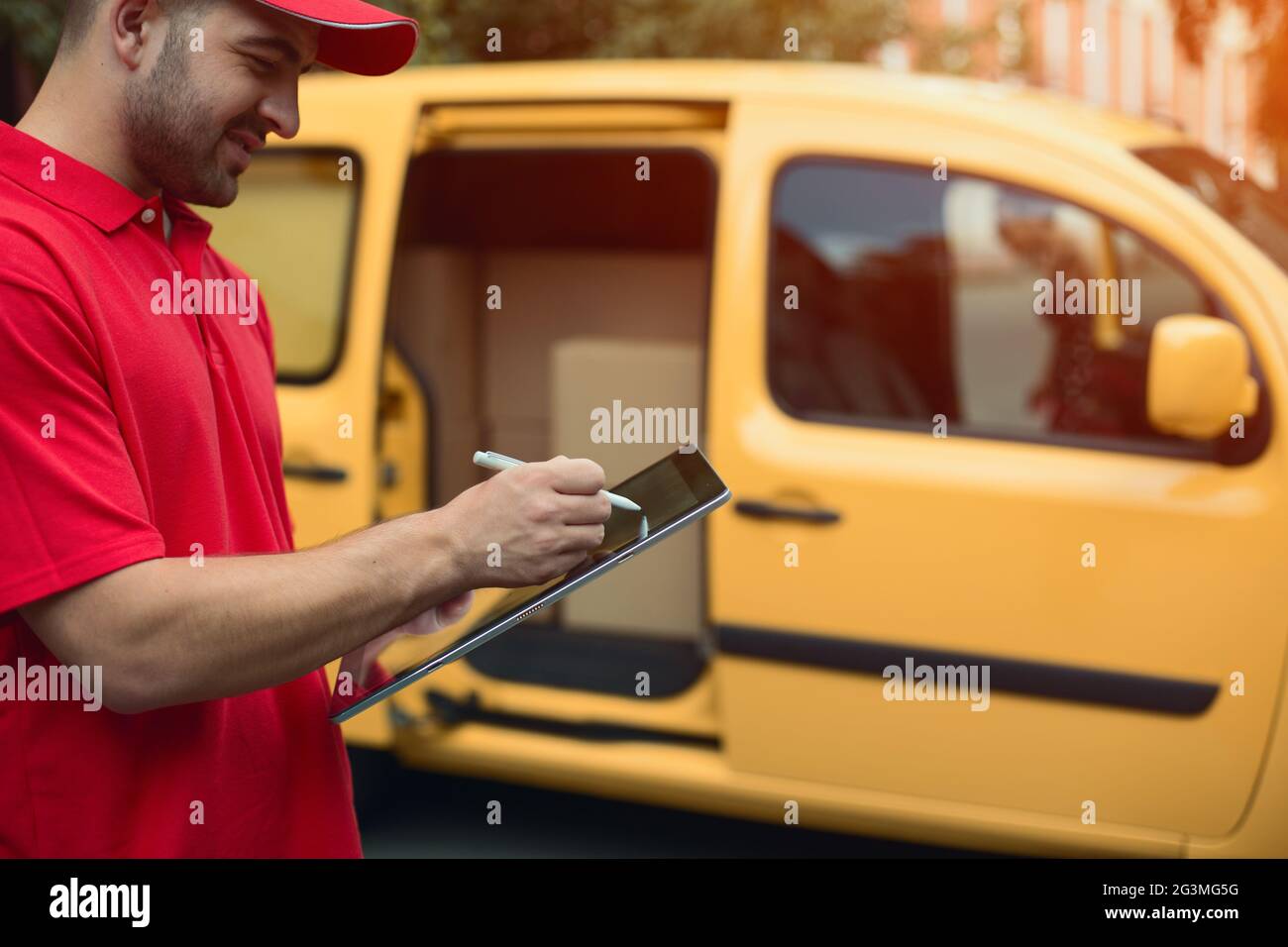 Delivery man signing digital tablet Stock Photo - Alamy