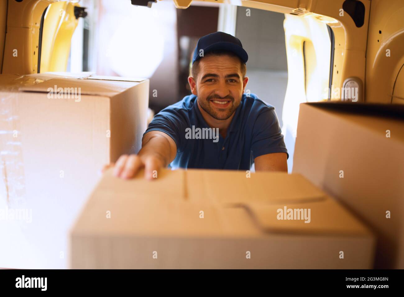 Delivery guy taking boxes out of van Stock Photo - Alamy