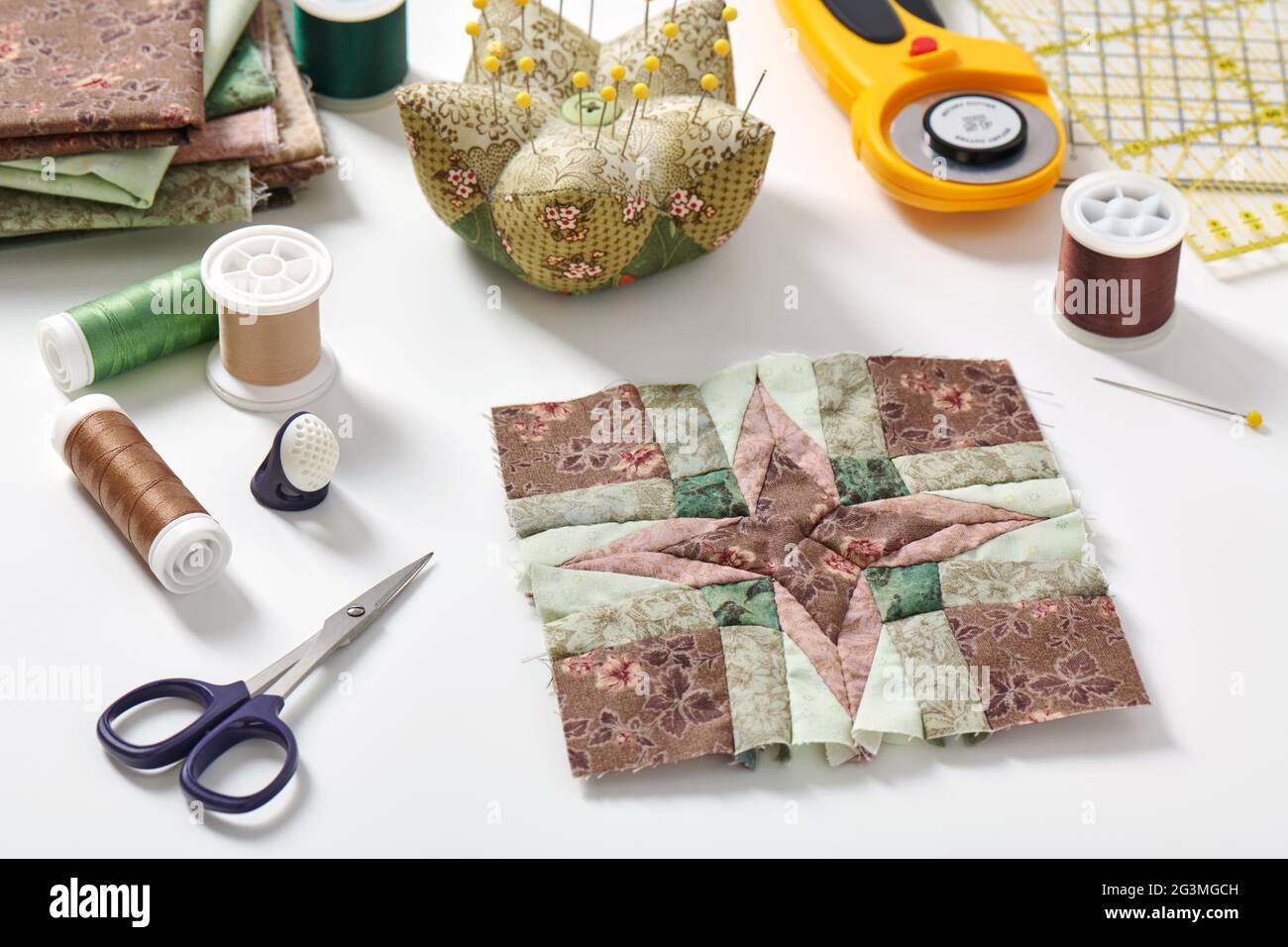 Patchwork block, stack of fabrics, pincushion, sewing and quilting ...