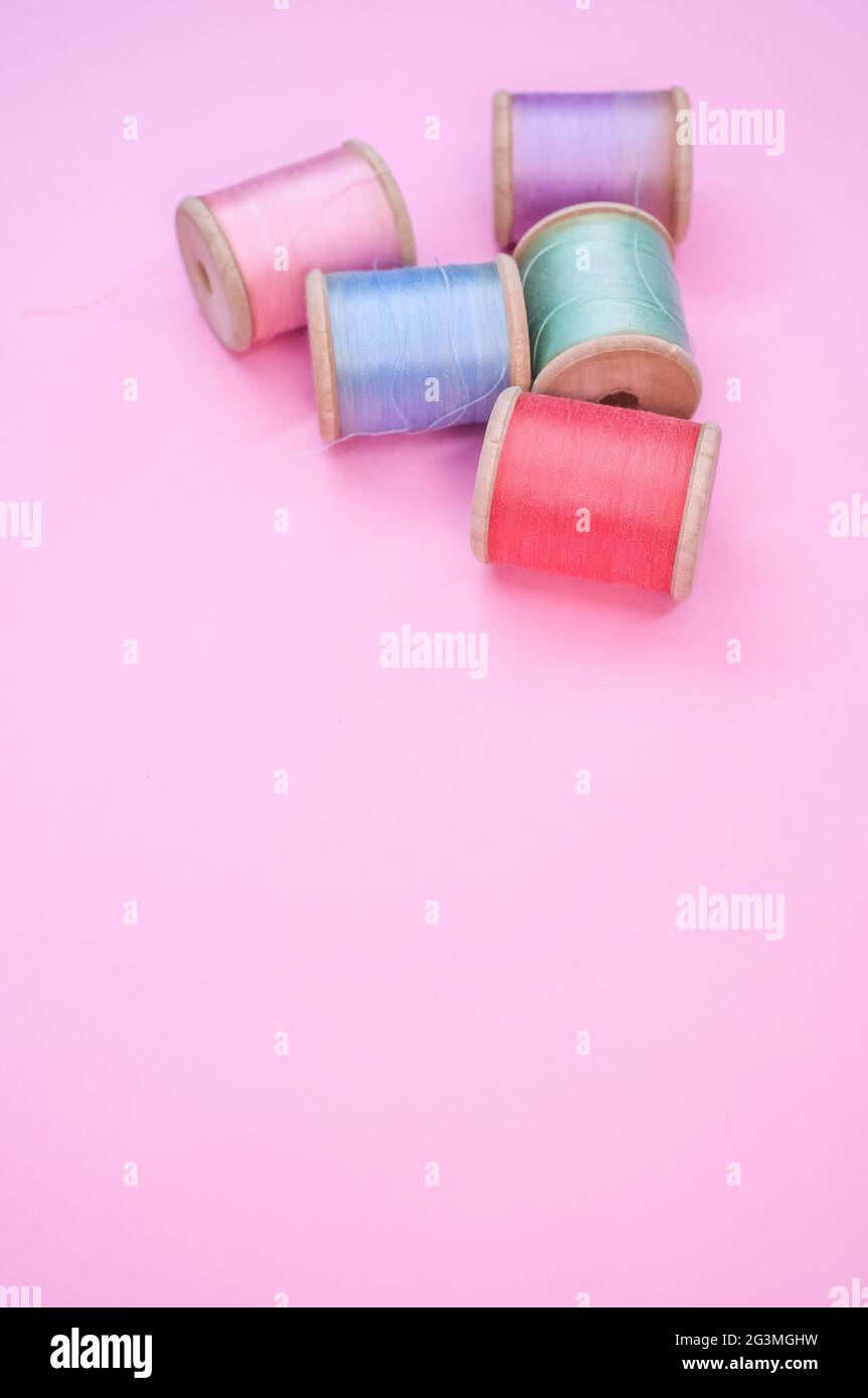 Colorful sewing threads isolated on a pink background with free space ...
