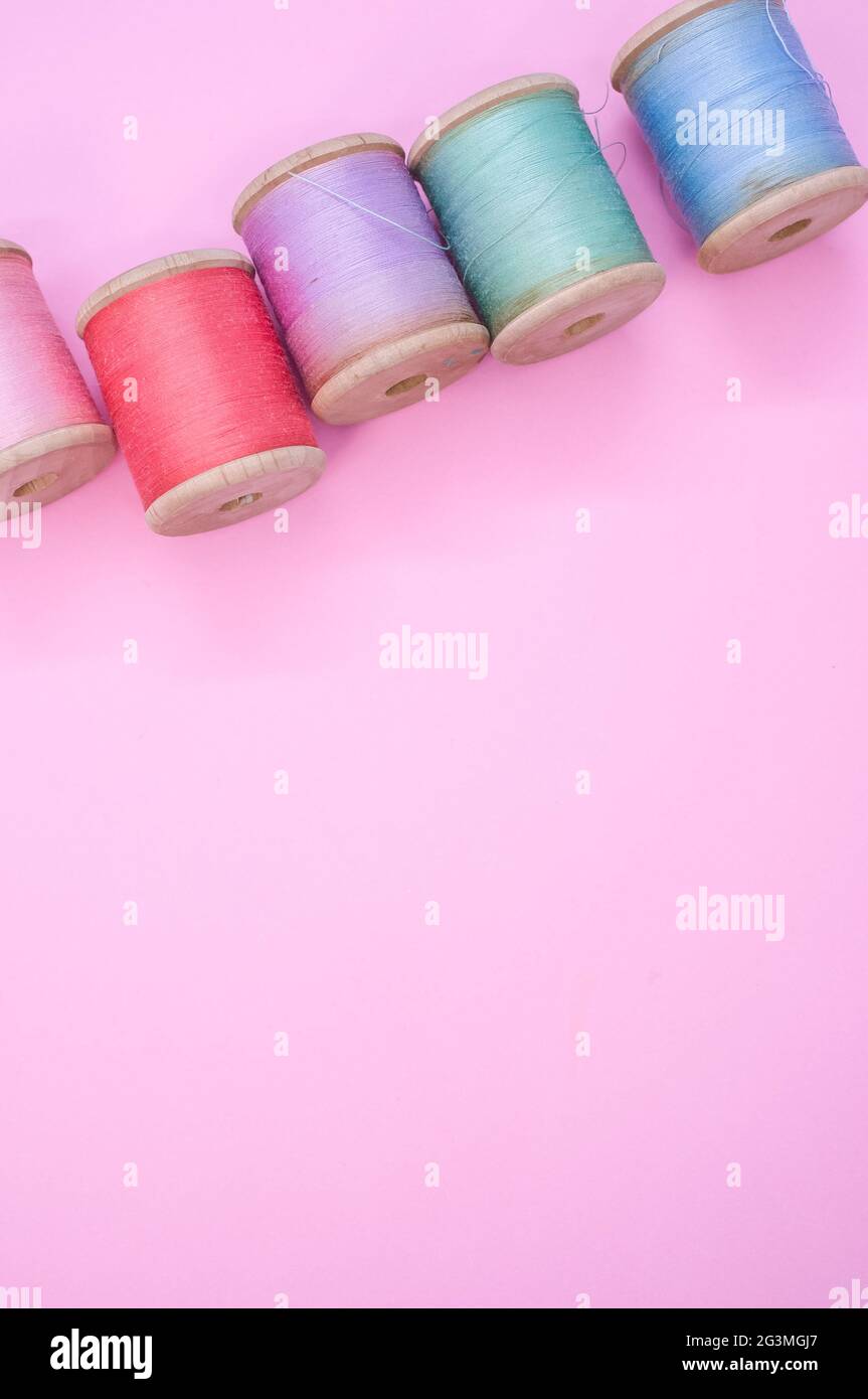Colorful sewing threads isolated on a pink background with free space ...