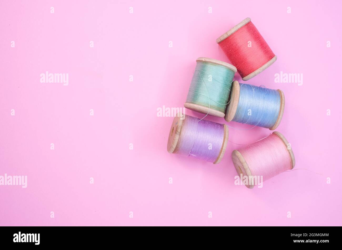 Colorful sewing threads isolated on a pink background with free space ...