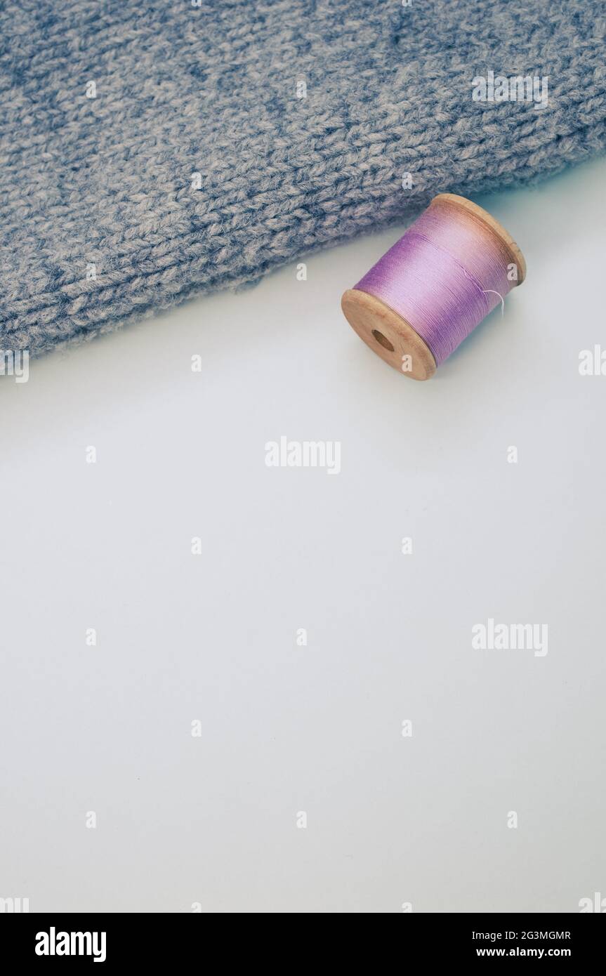 Purple sewing thread beside a grey fabric on a white background with ...