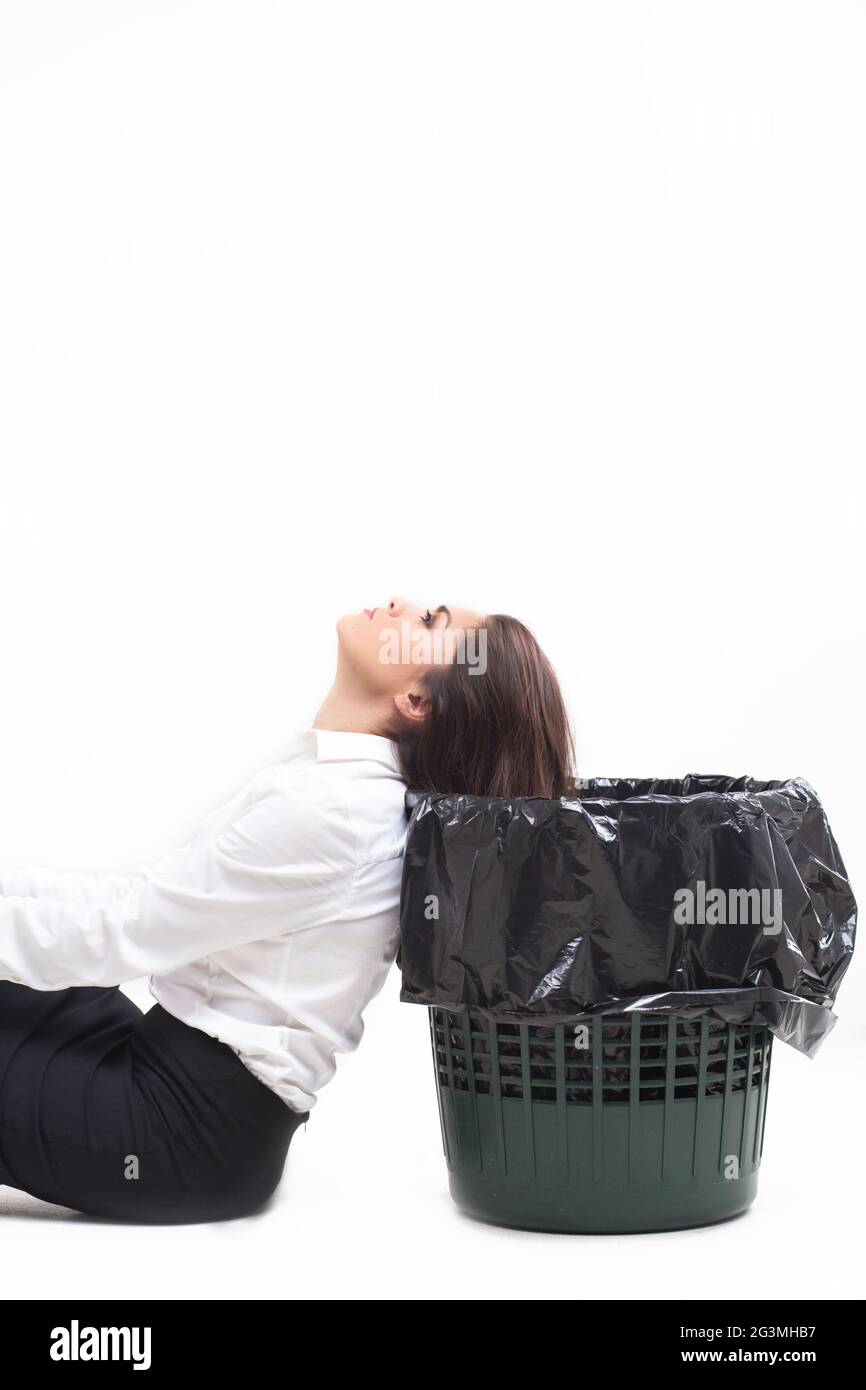 Girl sitting down next to trash bin Stock Photo - Alamy