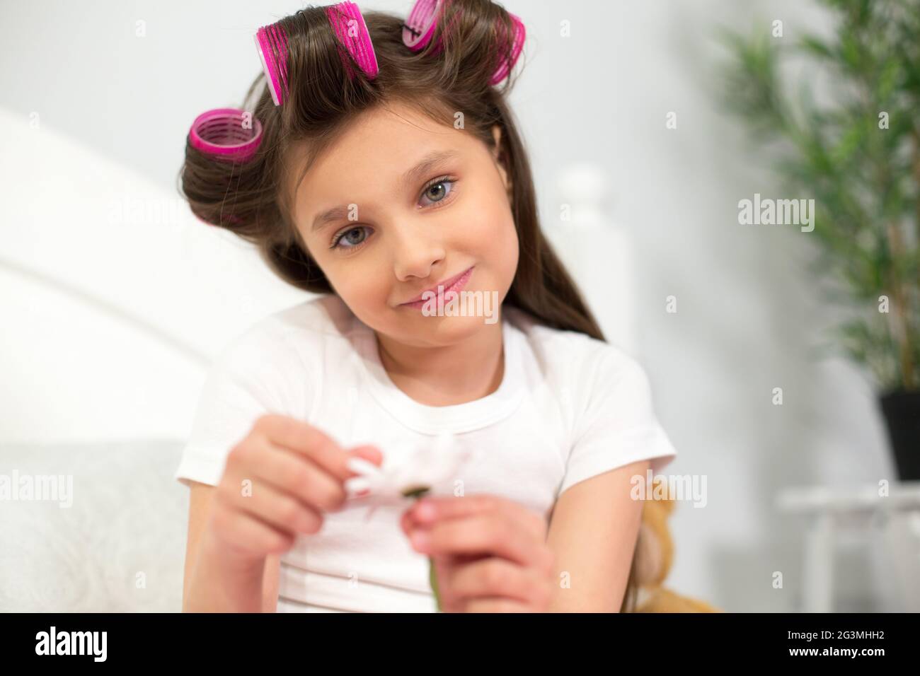 Young girl sitting on her bed with flower Stock Photo - Alamy