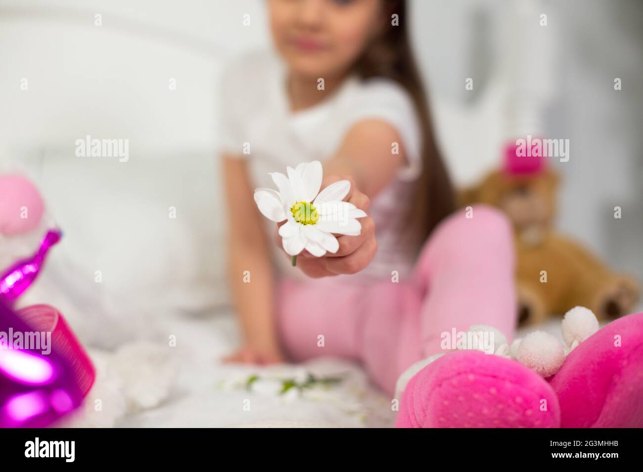 Young girl sitting on her bed with flower Stock Photo - Alamy
