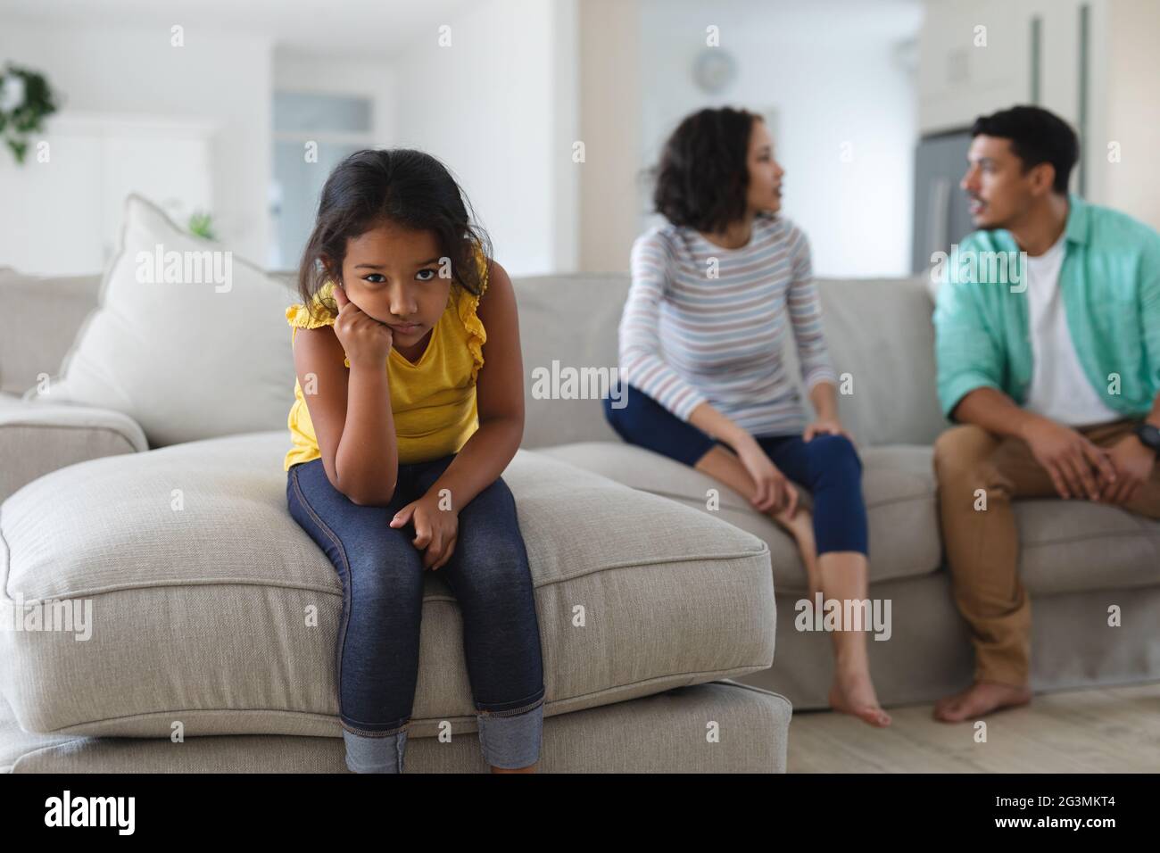 Sad hispanic daughter sitting on couch with mother and father arguing ...