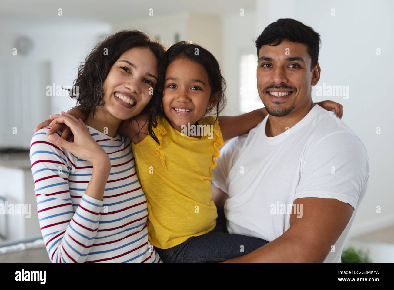 Portrait of smiling hispanic father embracing with wife and daughter ...