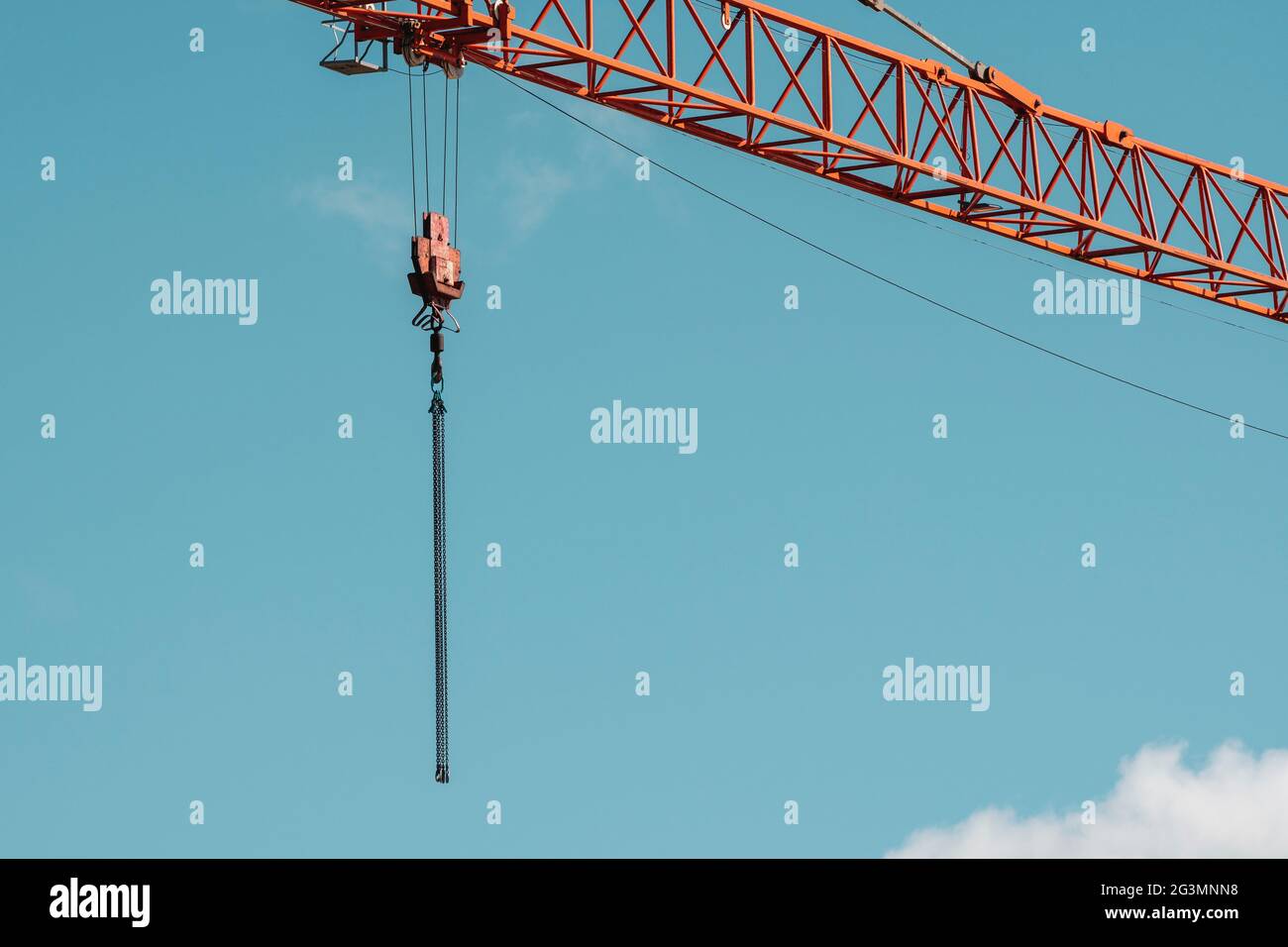Orange crane boom with hooks and blue sky background Stock Photo - Alamy