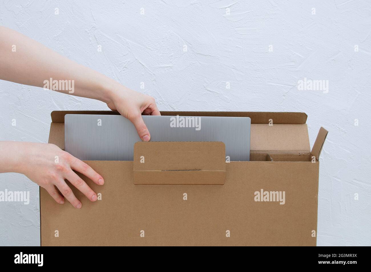 Unpacking a laptop from a cardboard box. Hands of a Caucasian woman ...