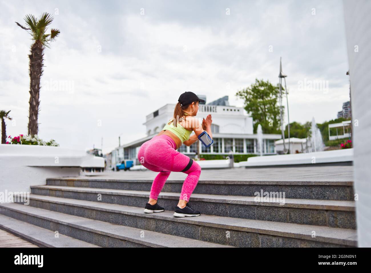 Fit woman in sportswear jumps with fitness gum expander on the stairs ...