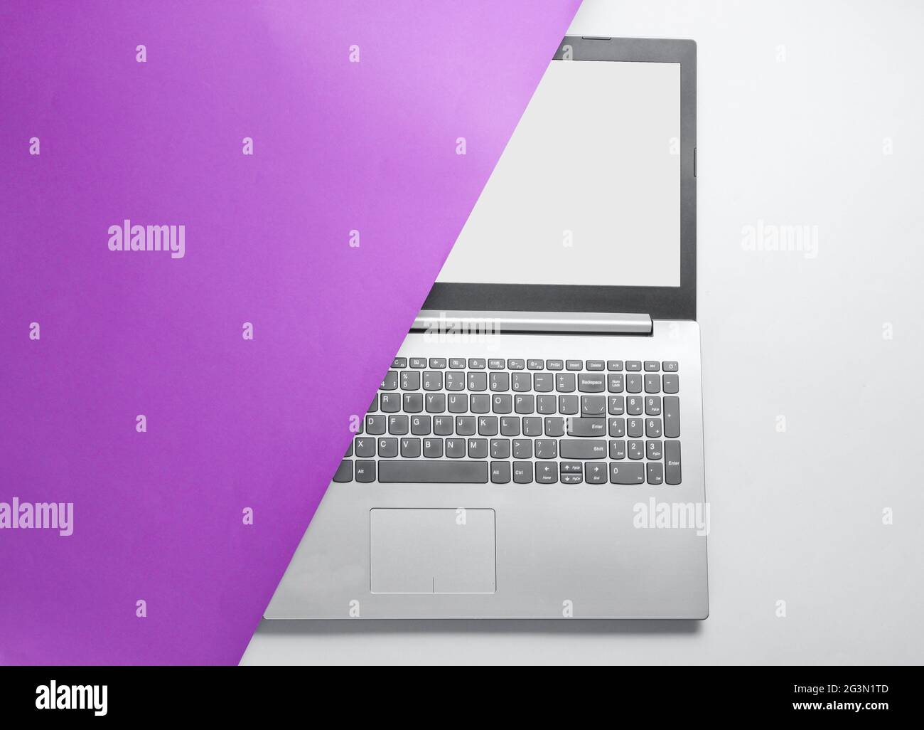 Half of laptop hidden behind purple paper sheet. Minimalism concept ...