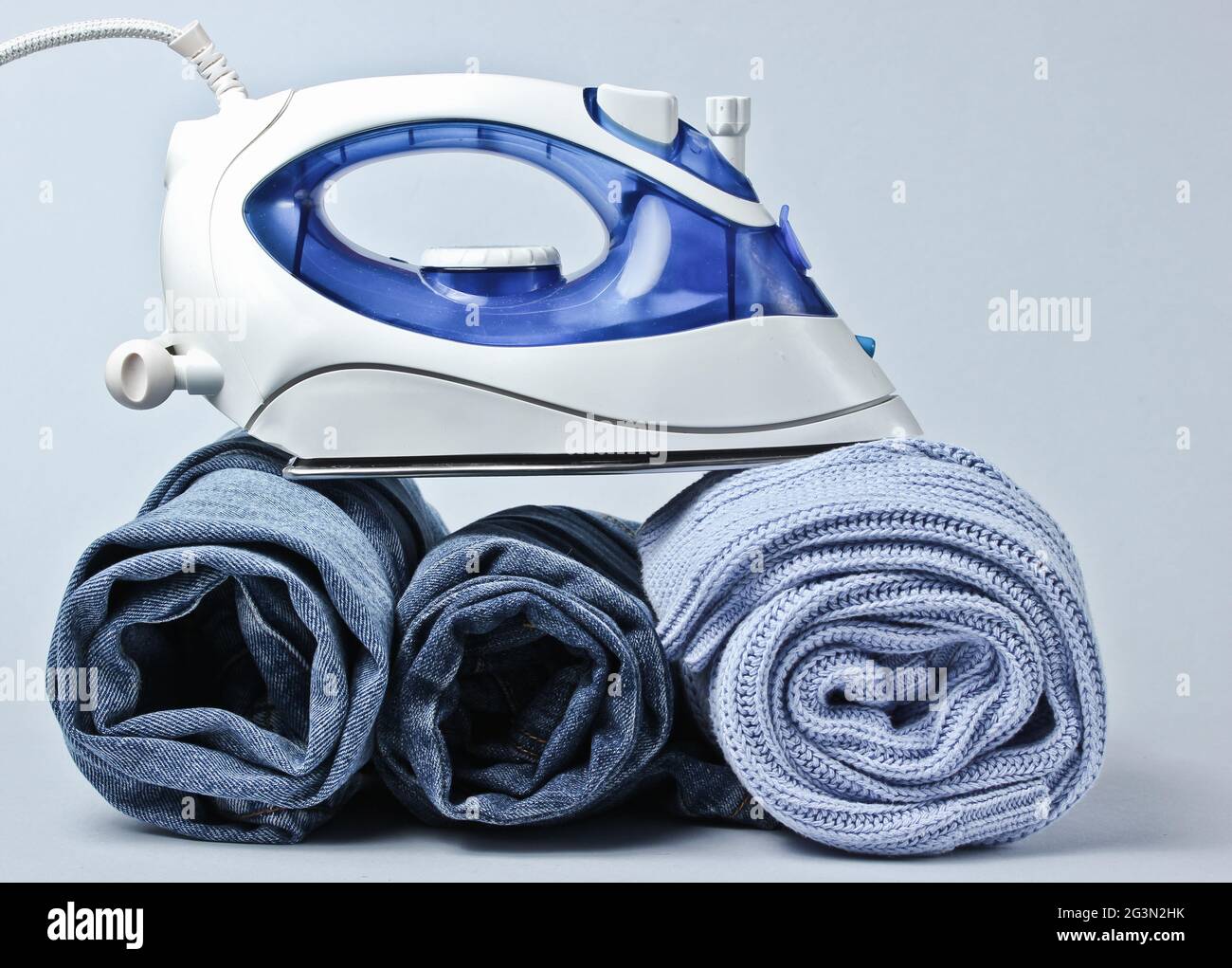 iron on rolled clothes on gray background Stock Photo - Alamy