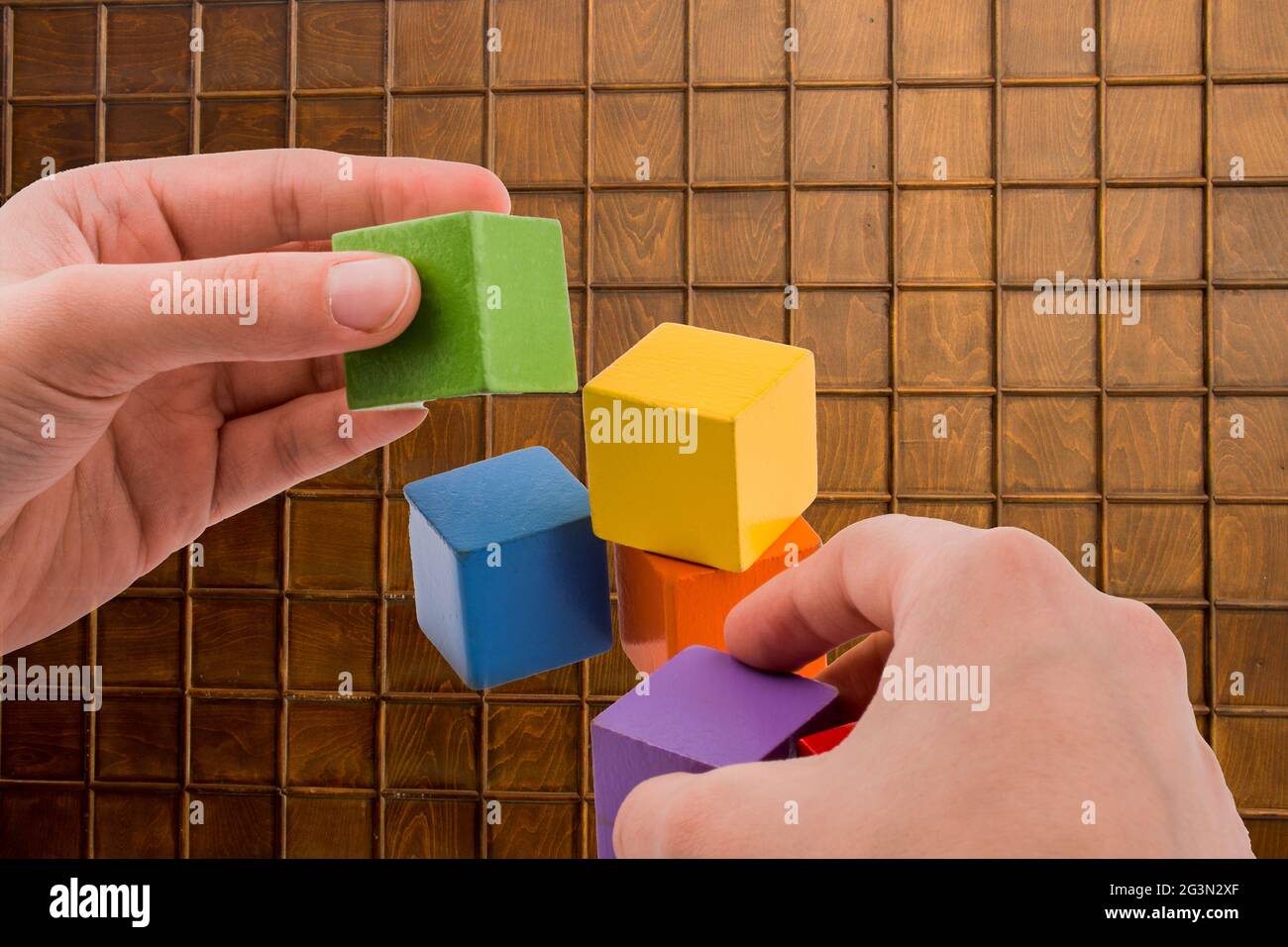Hand building colorful cubes on a background Stock Photo - Alamy