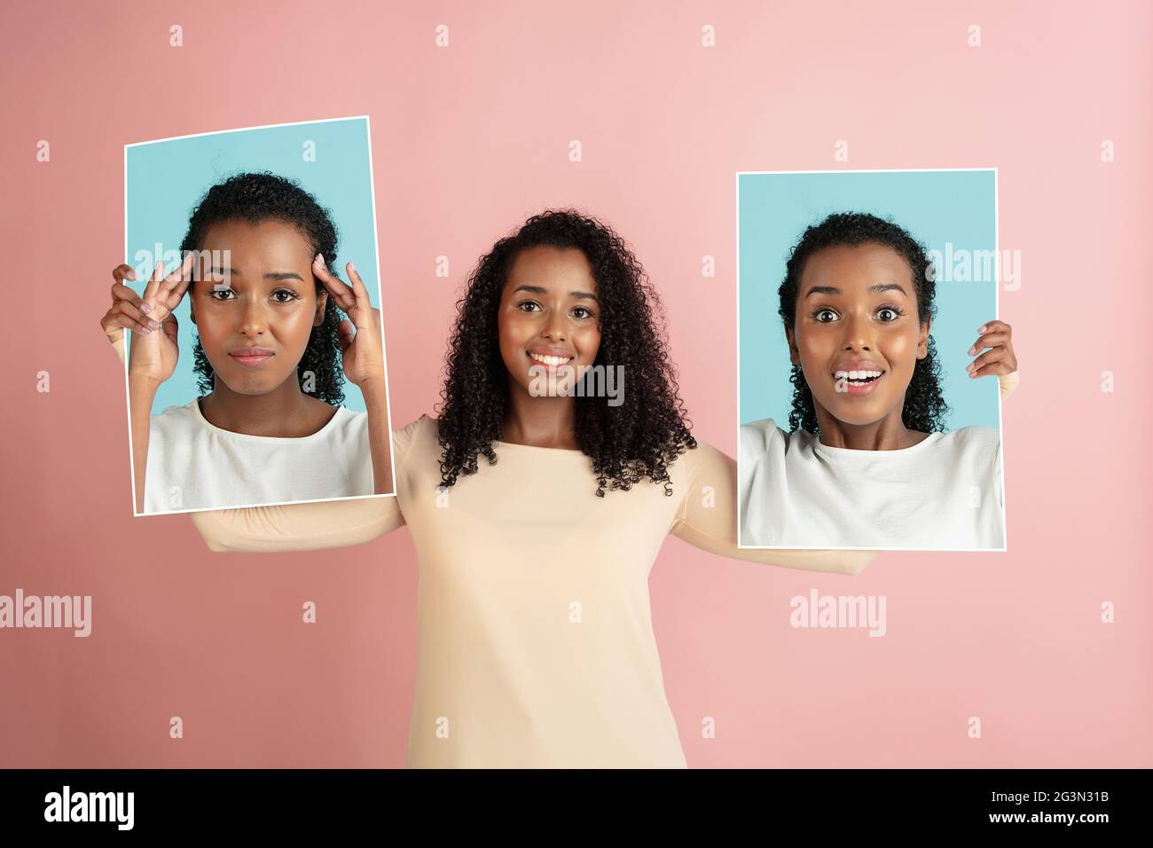 Young attractive girl holding her portraits, pictures isolated on light ...