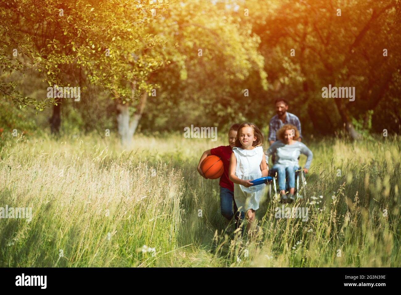 Children ran and laugh while their mother on wheelchair and father are ...