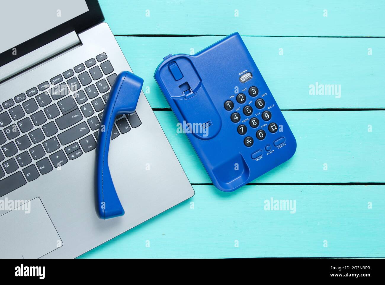Work space call center. Laptop, office phone on a blue wooden ...
