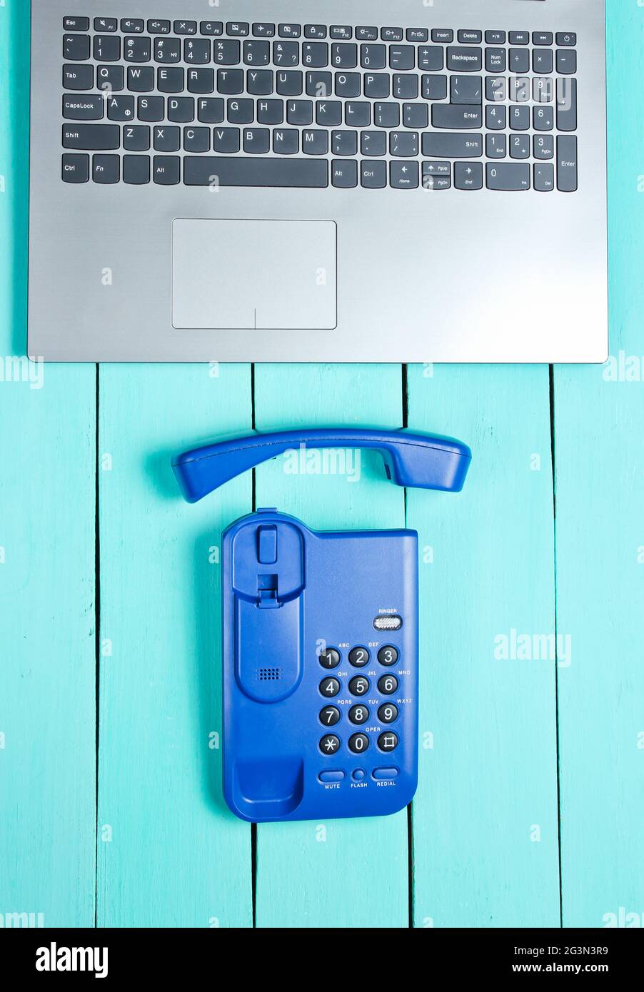 Work space call center. Laptop, office phone on a blue wooden ...