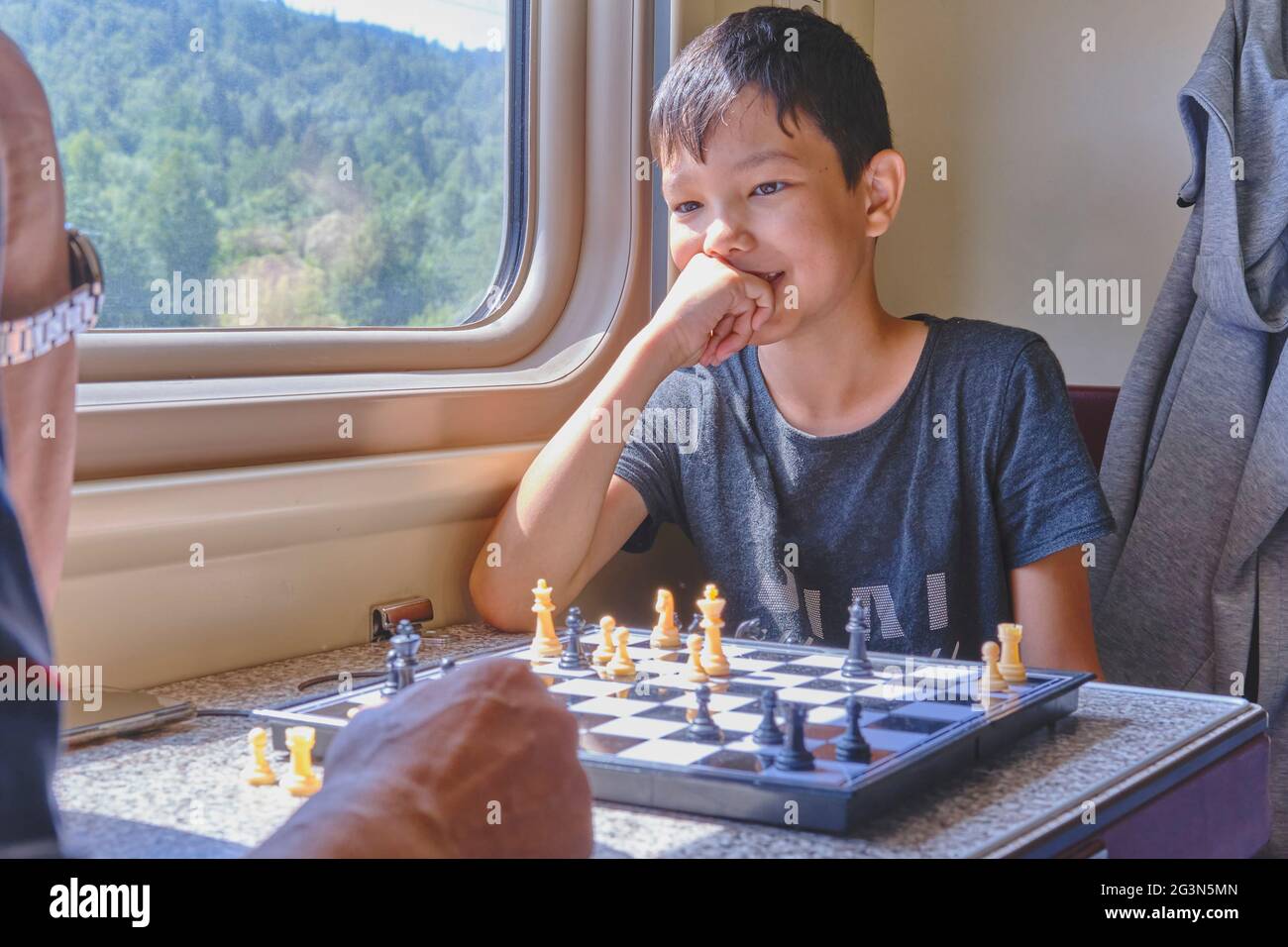 Asian boy smiling and playing chess in the train Travel, table games ...