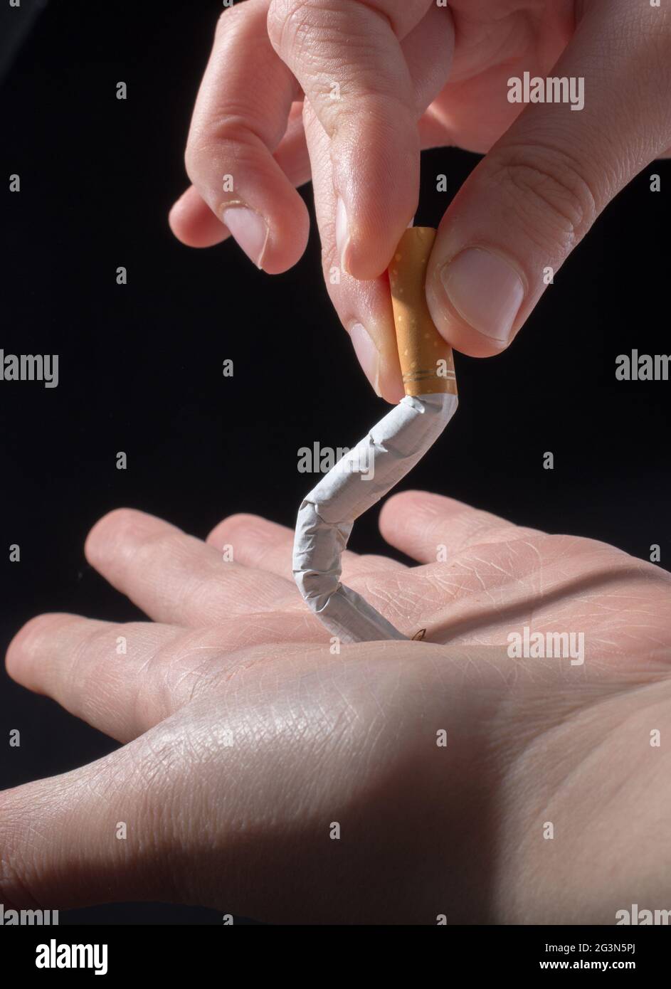 Hand is breaking a cigarette on black background Stock Photo - Alamy