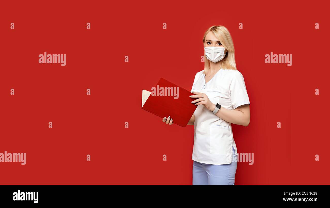 Confident female doctor wearing protective face mask standing on red ...