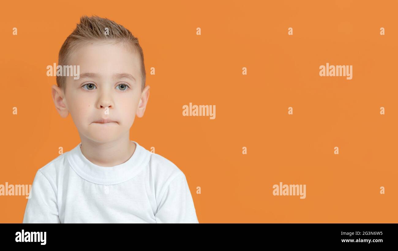 Portrait of a cute brooding kid with a squeezed lip . A serious boy ...