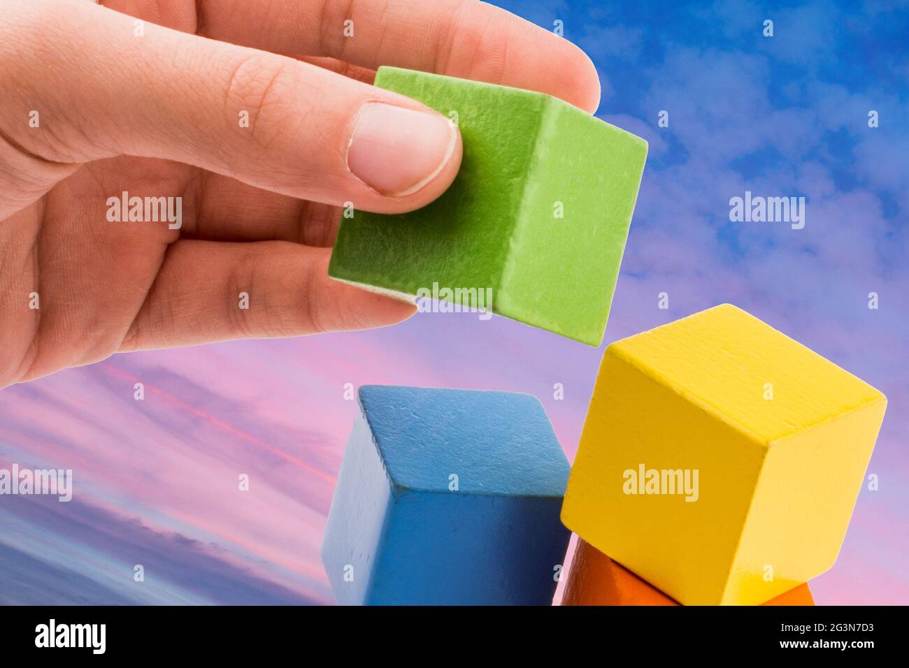 Hand building colorful cubes on a background Stock Photo - Alamy
