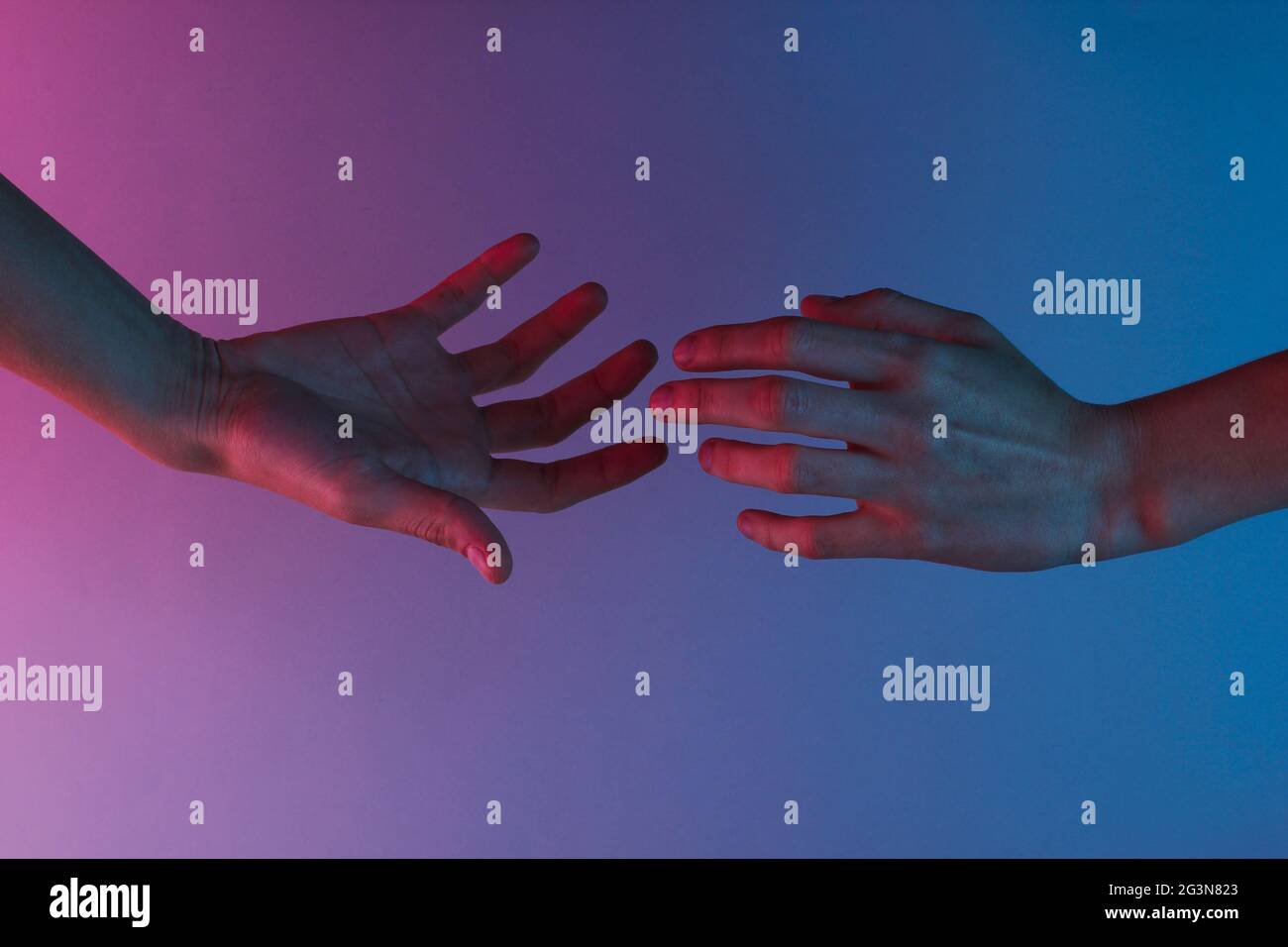 Two hands reach out to each other with a red-blue neon light ...