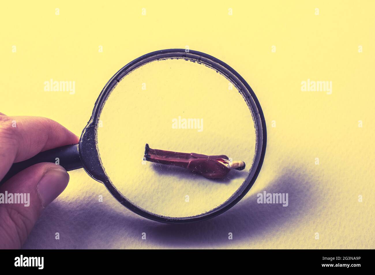 Tiny figurine of man model under magnifying glass Stock Photo - Alamy