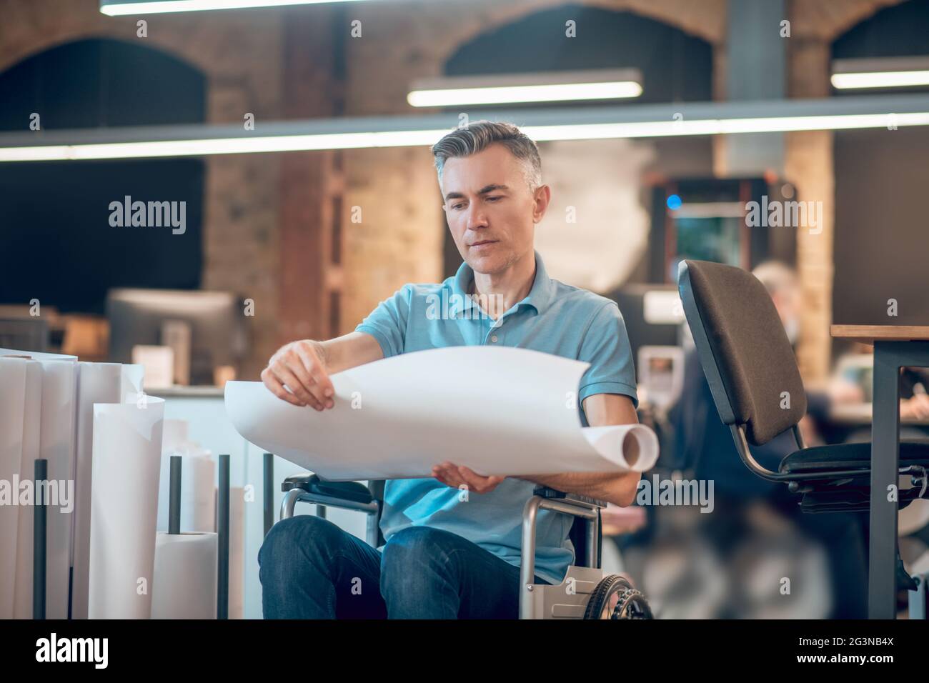 Man in wheelchair unrolling roll of paper Stock Photo - Alamy