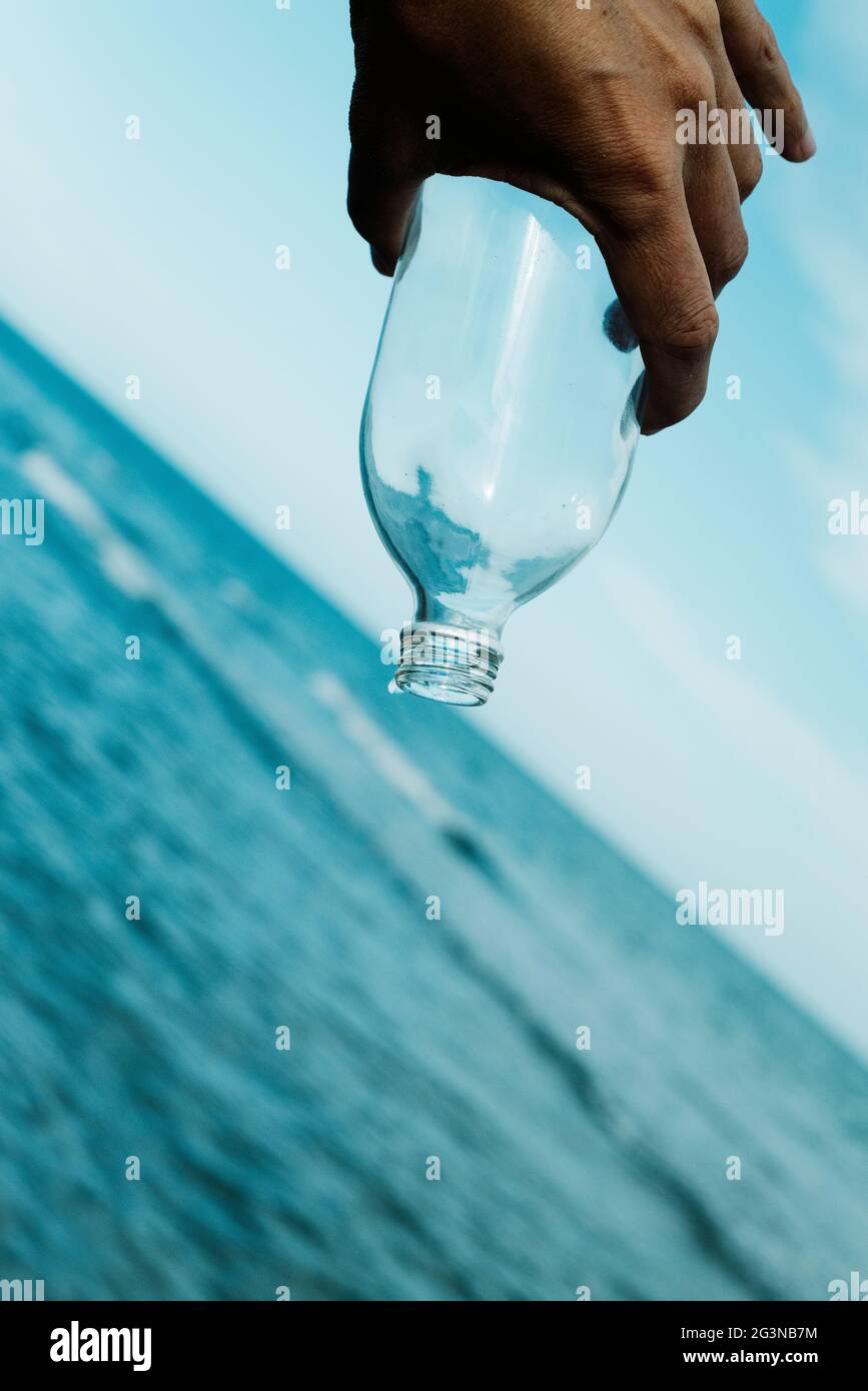 a drop of water falls from an emptied reusable glass water bottle ...