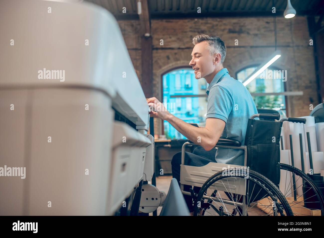 Disabled man working with copy machine Stock Photo - Alamy