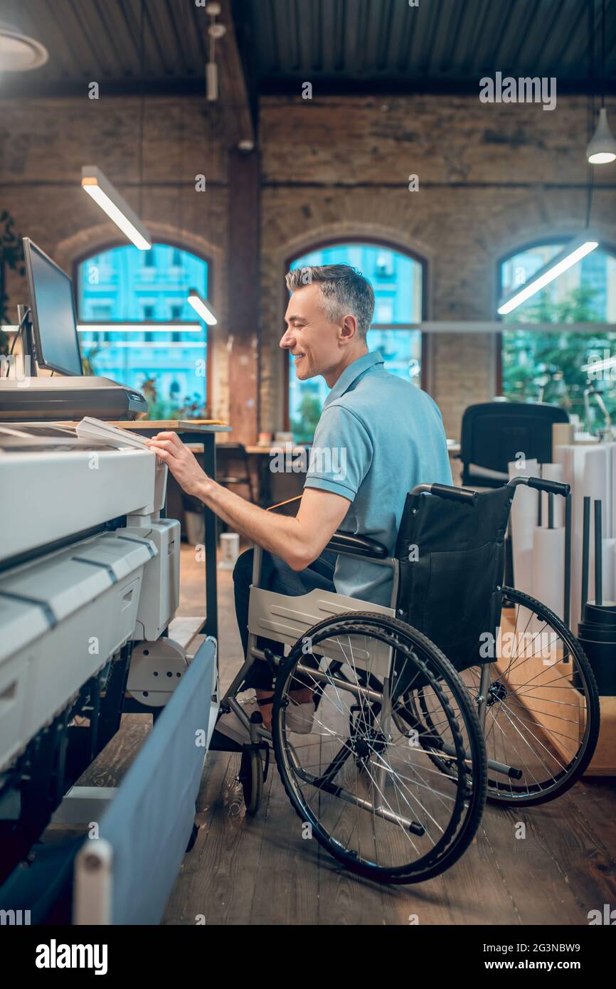 Smiling disabled man at workplace near copy machine Stock Photo - Alamy