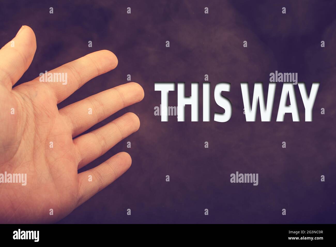 Hand making welcome gesture with THIS WAY word Stock Photo - Alamy