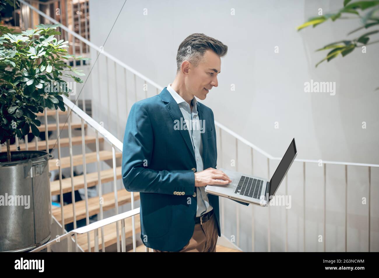 Profile of man looking at laptop standing on stairs Stock Photo - Alamy