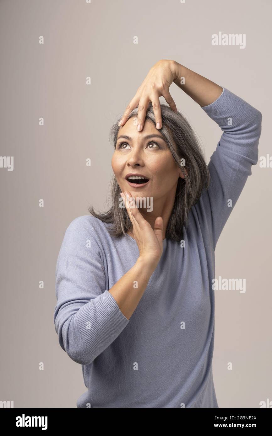 Attractive Asian woman is emotionally posing touching her head with ...