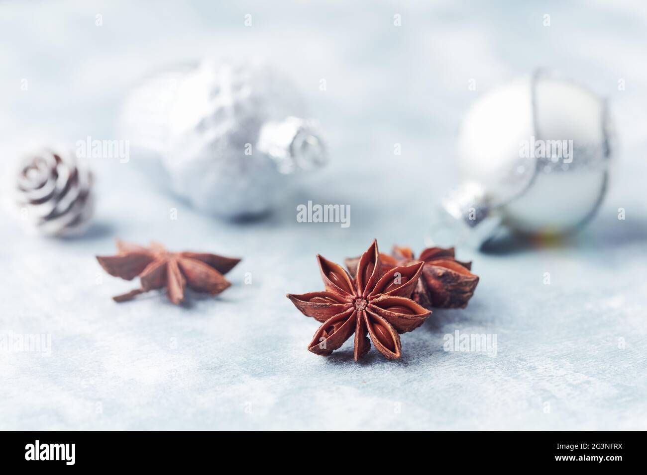 Star anise and silver Christmas ball on bright wooden background. Close ...