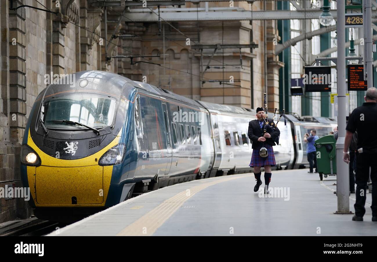A piper walks the platform alongside the Avanti West Coast Class 390 ...