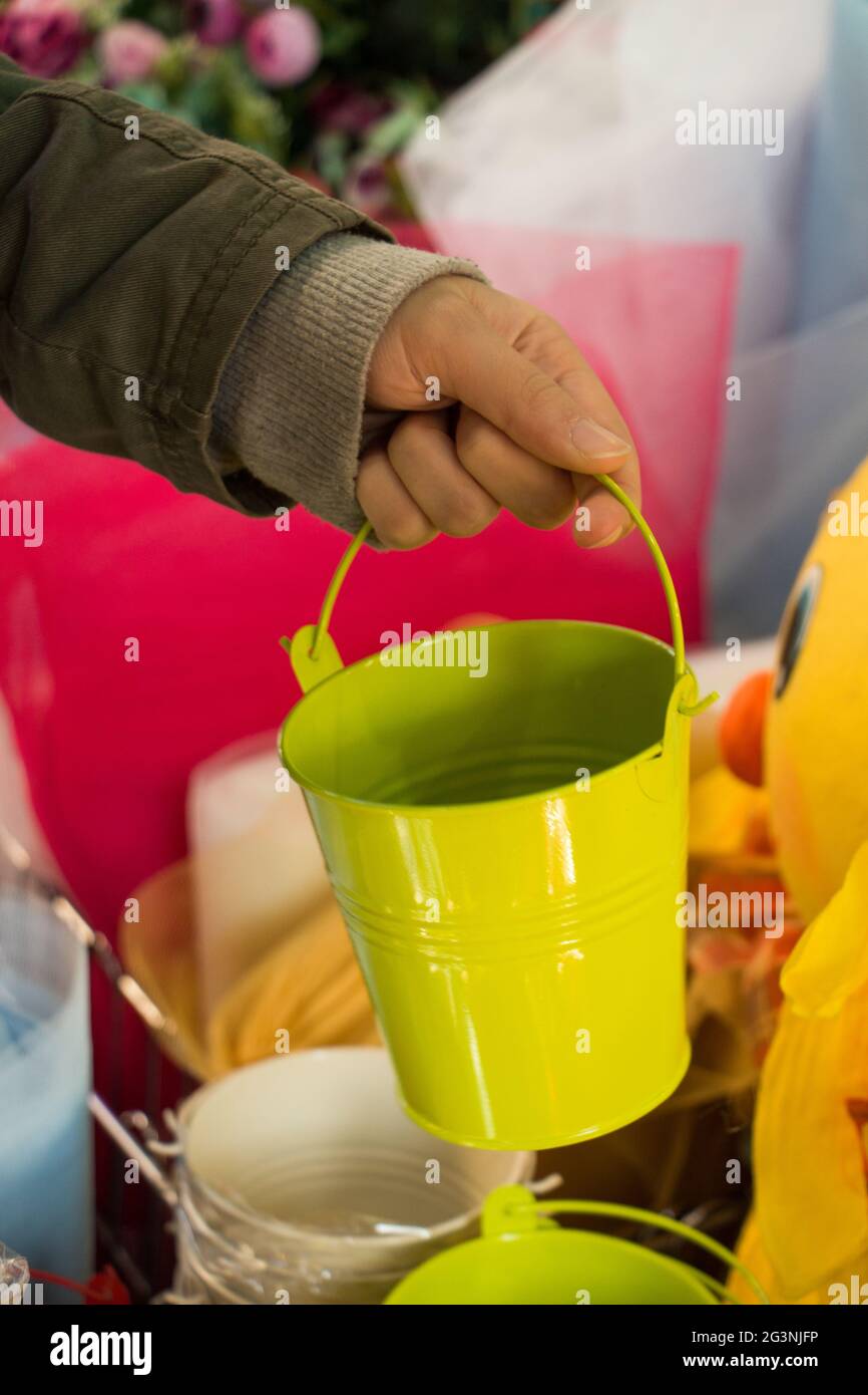 Hand holding a green little bucket for sale Stock Photo - Alamy