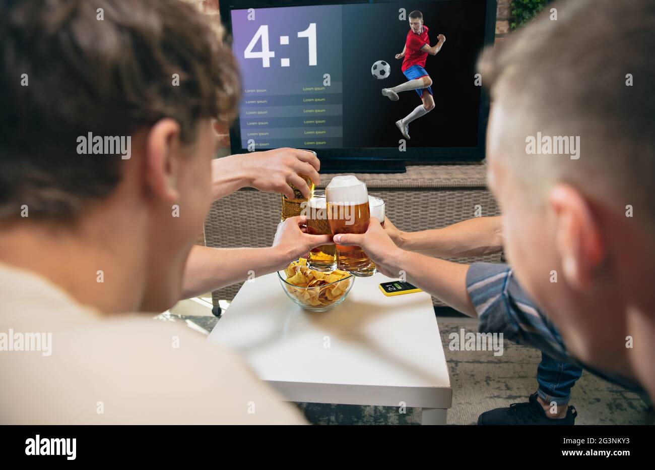High angle view of young people watching TV, sport match together ...